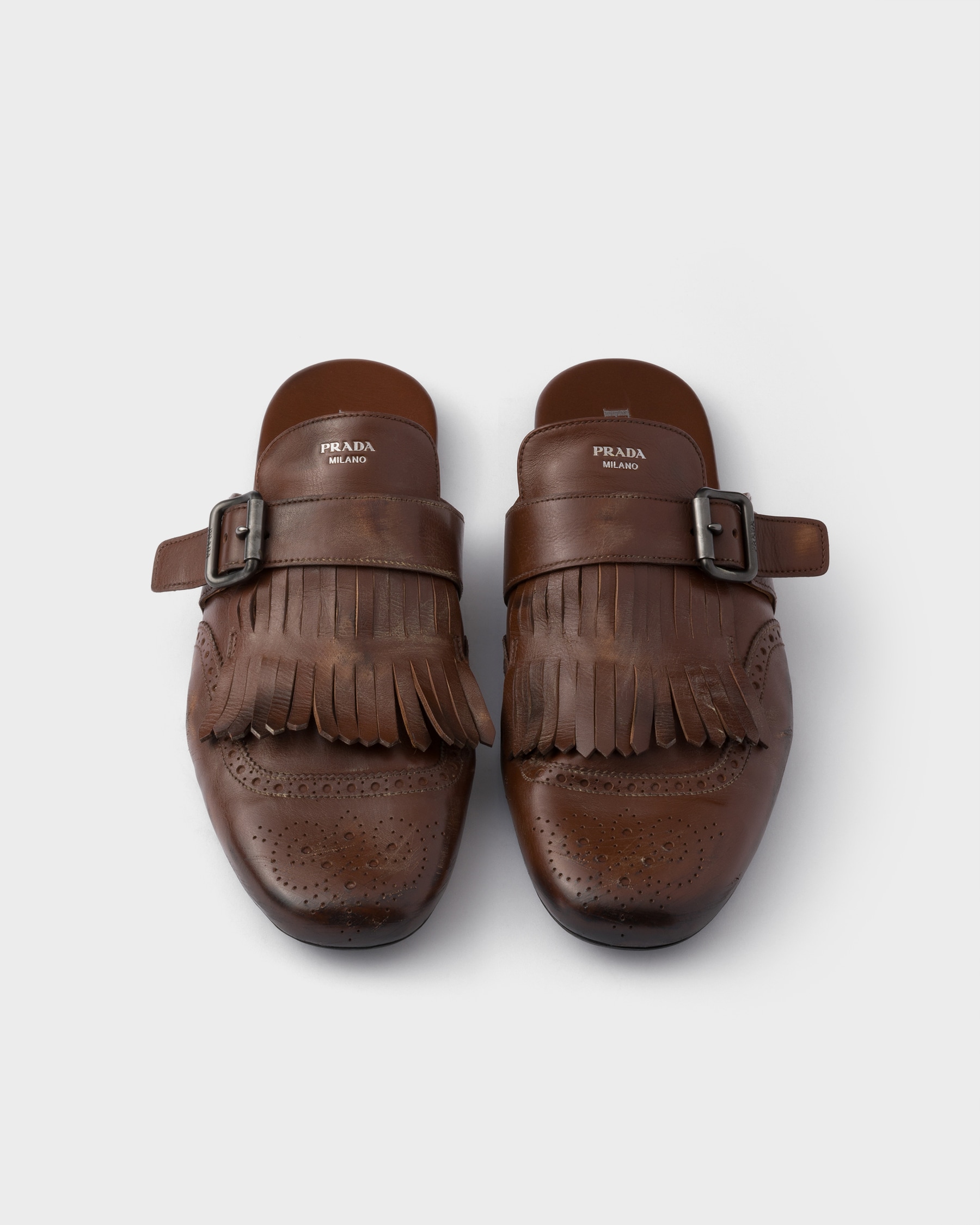 Cognac Shuffle Antiqued Leather Mules With Buckled Strap And Fringe | PRADA